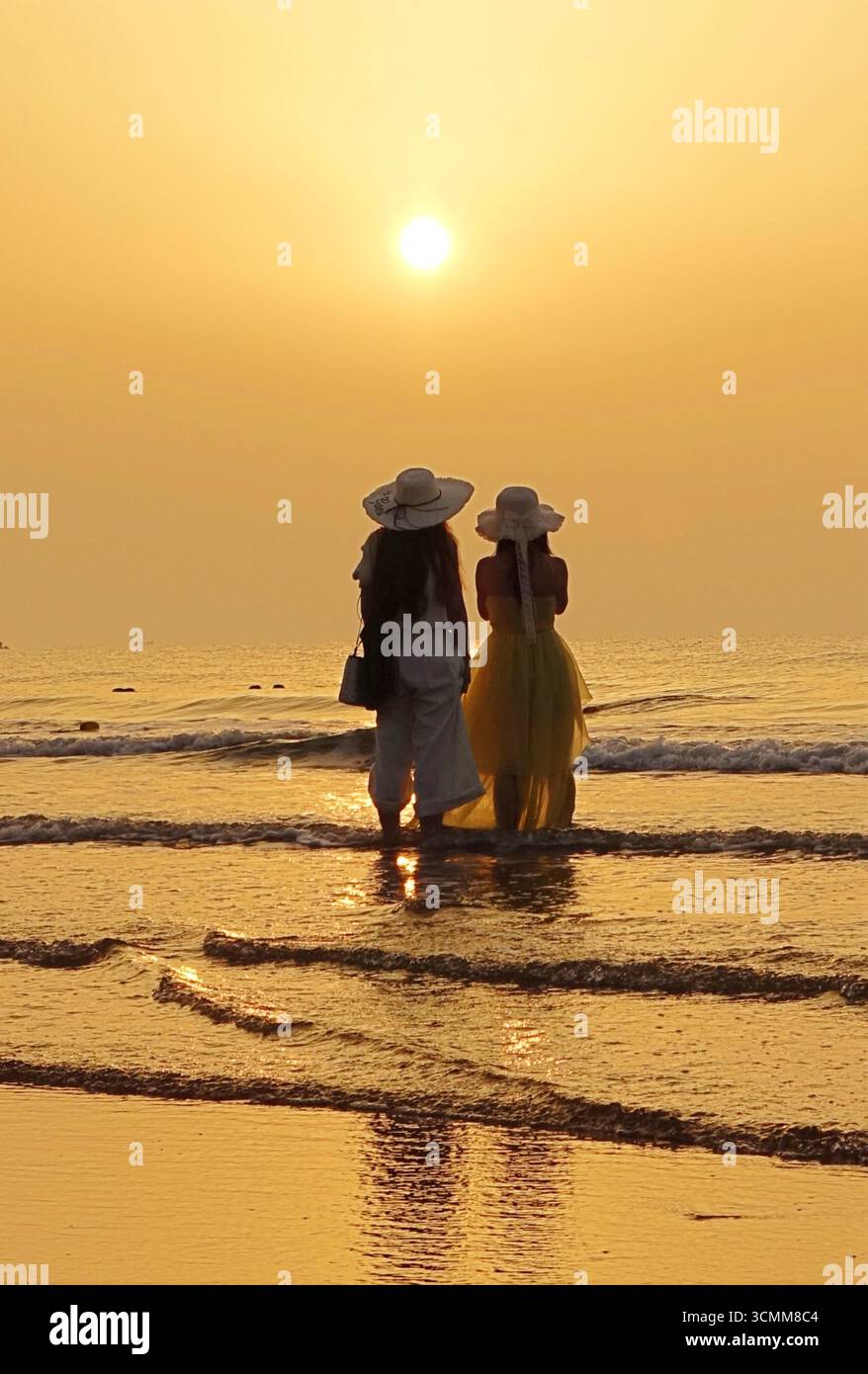 Tourists watch the sunrise at the golden beach in Qingdao City, east ...