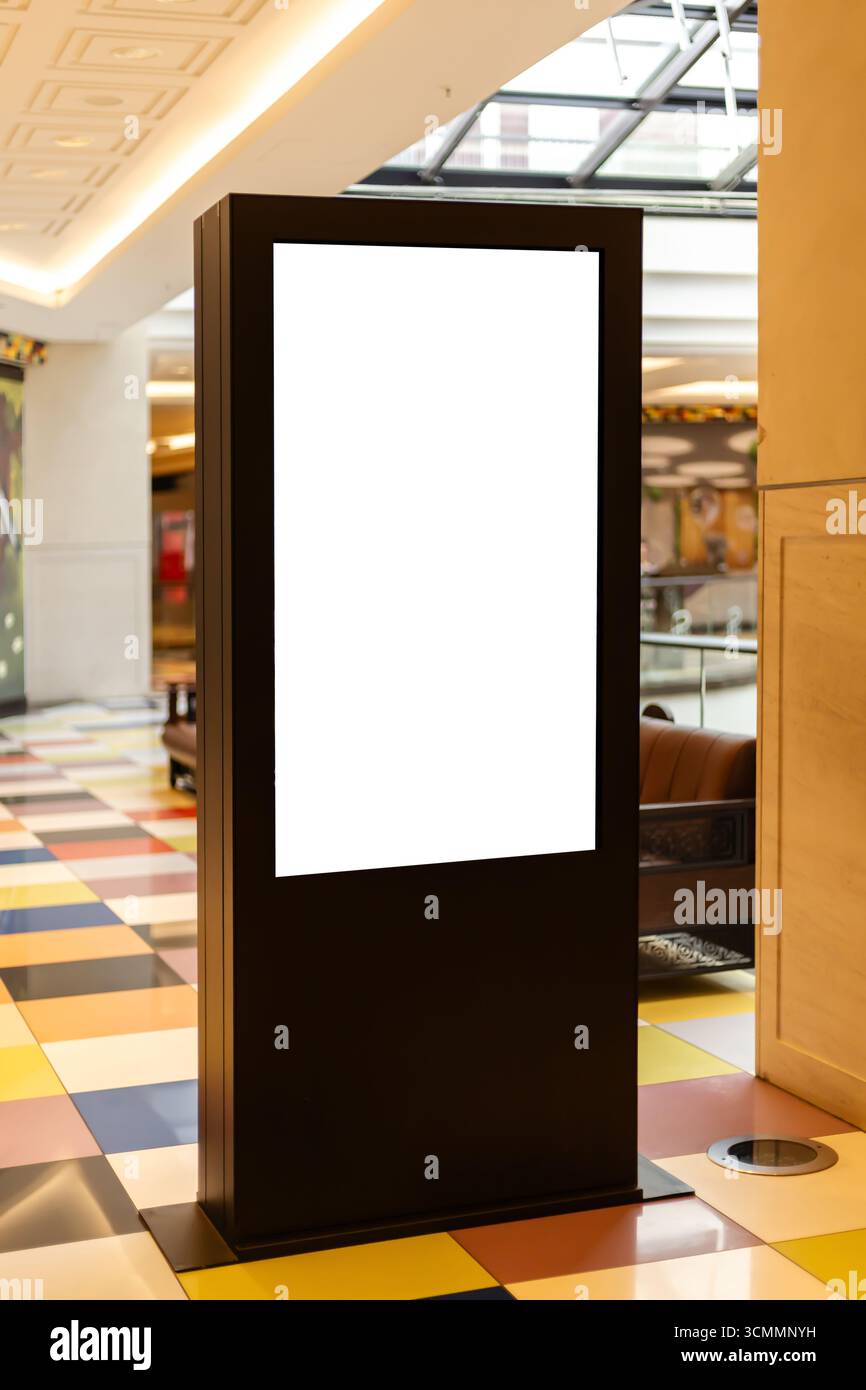 A tall digital display stand is placed indoors at a vibrant shopping ...