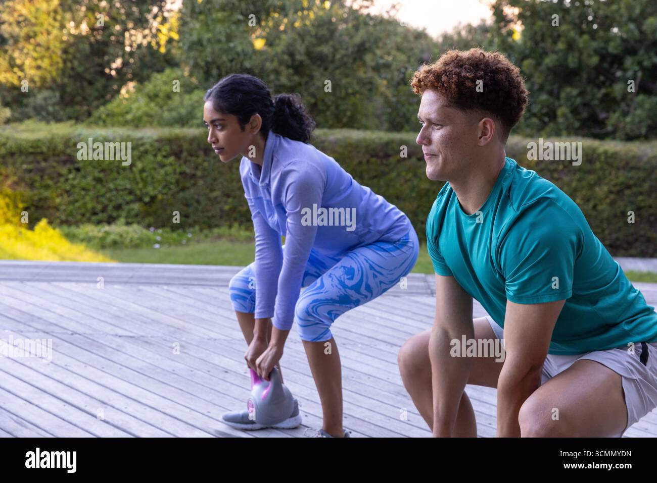 Diverse workout partners performing kettlebell deadlifts wearing ...