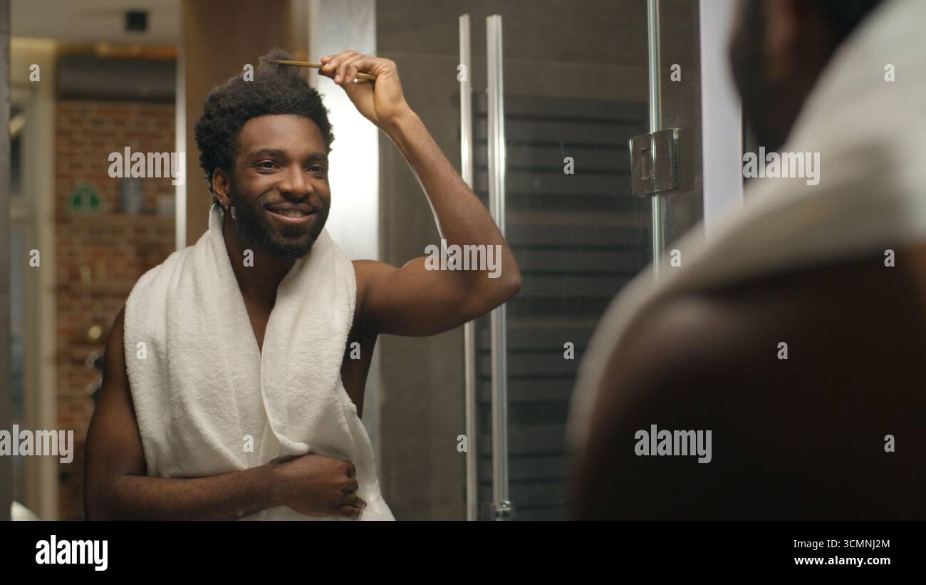 African American man looking at mirror reflection brush hair in ...