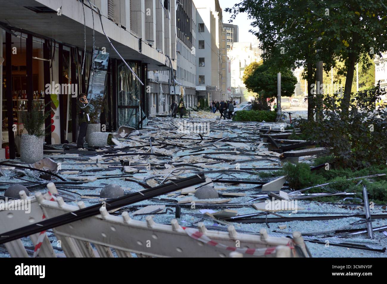 People are standing near a pile of glass facade panels from a building ...