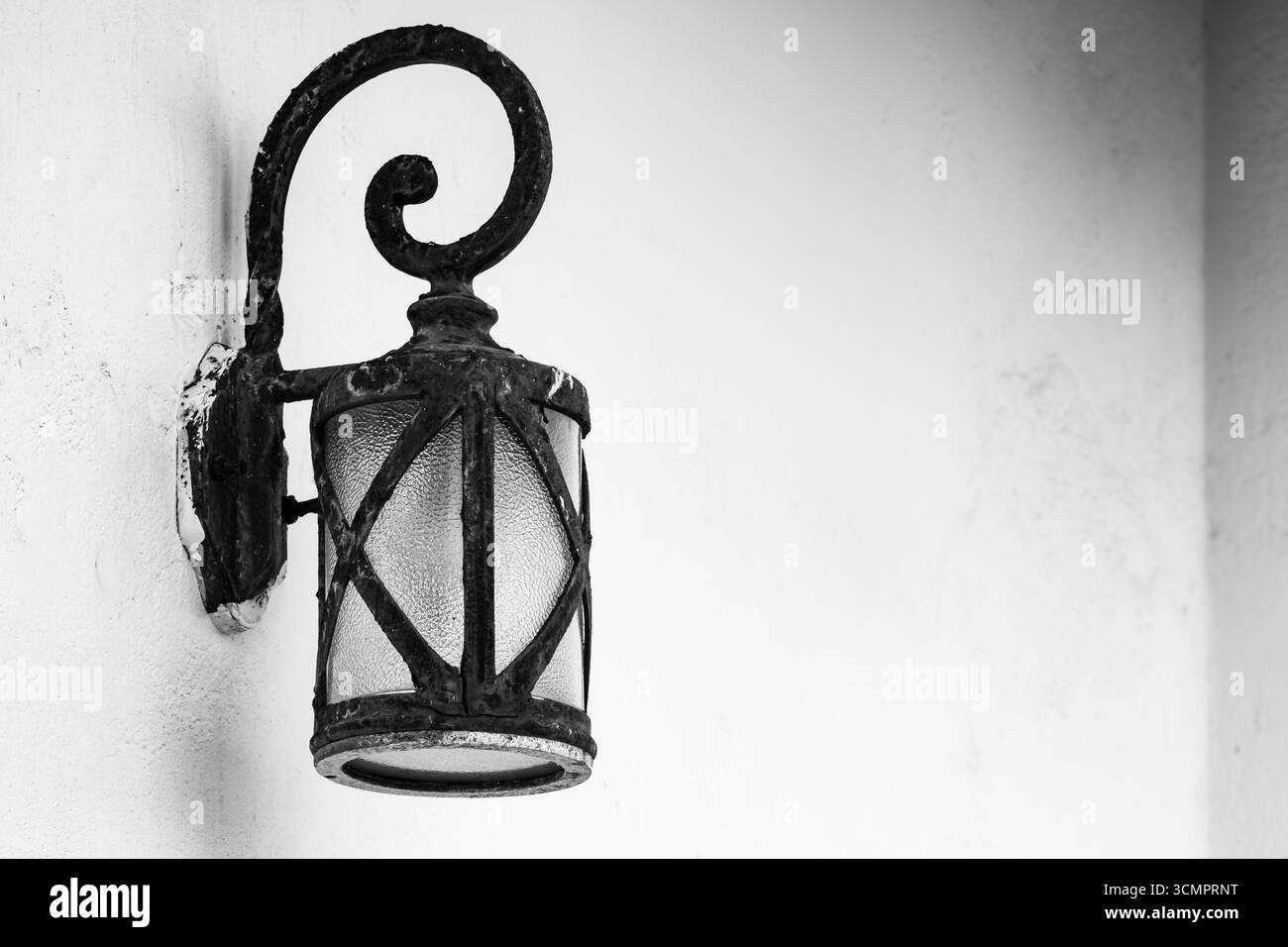 Ancient black metal wrought iron lantern hanging on the stone wall ...