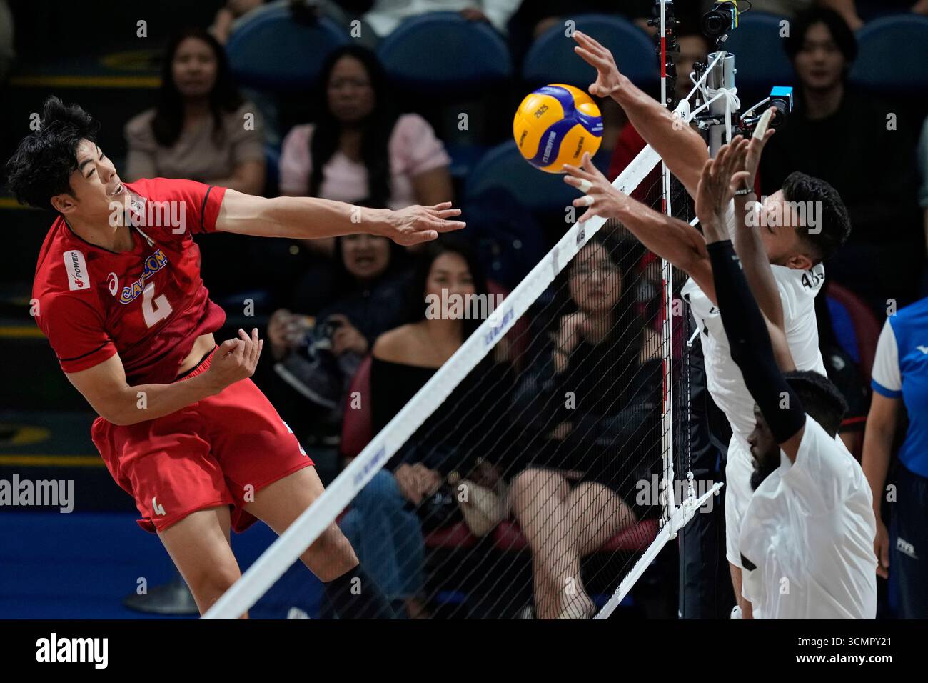 Kento Miyaura, left, of Japan spikes the ball against Libya players ...