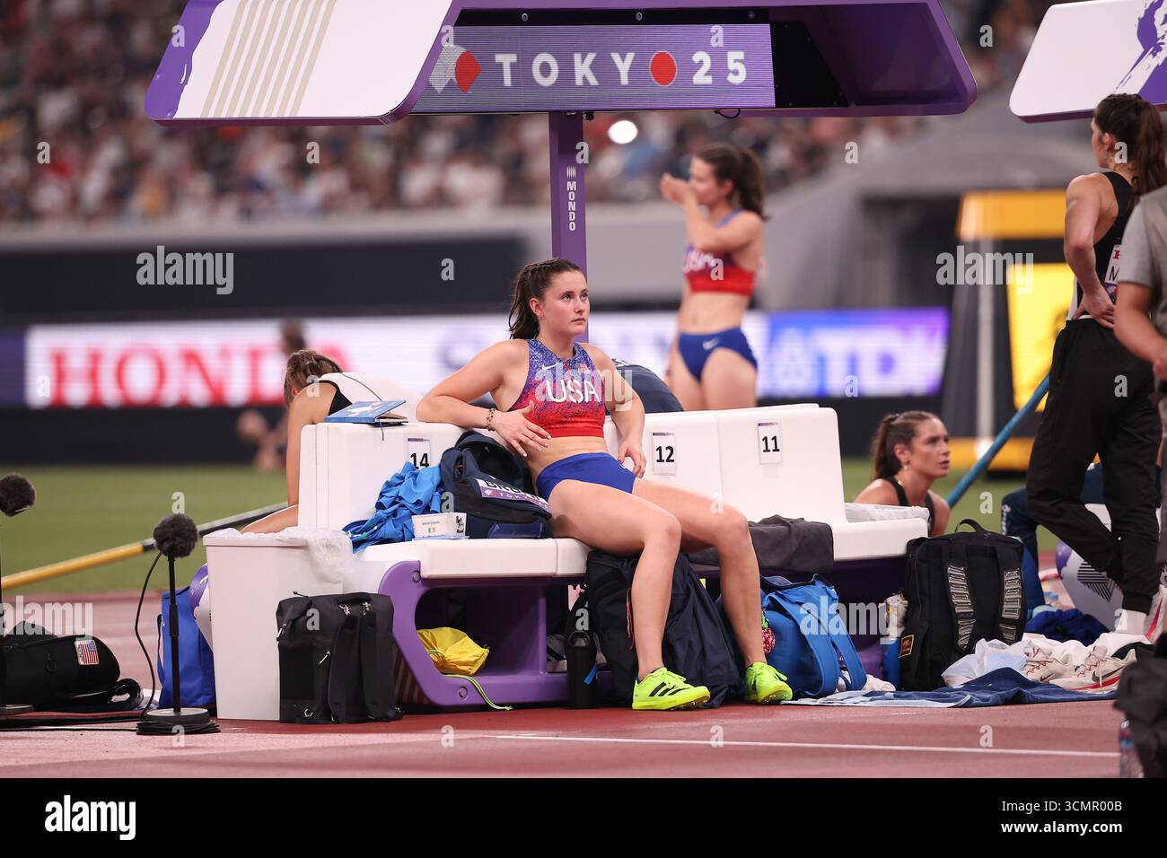 Amanda Moll (USA) sits as twin sister Hana Moll (USA) prepares to vault ...