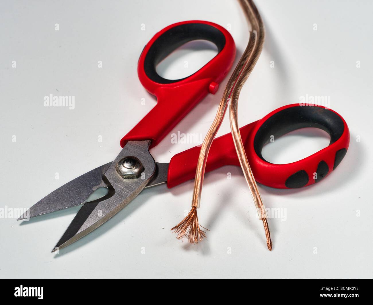 Cutting electrical wire with a pair of scissors - A pair of red-handled ...