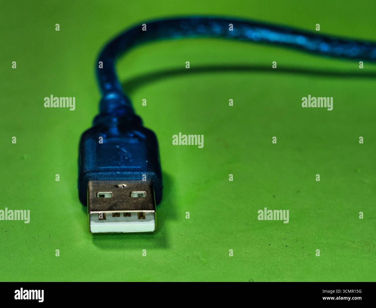 Blue USB cable on a vibrant green background - A single, blue USB Type ...