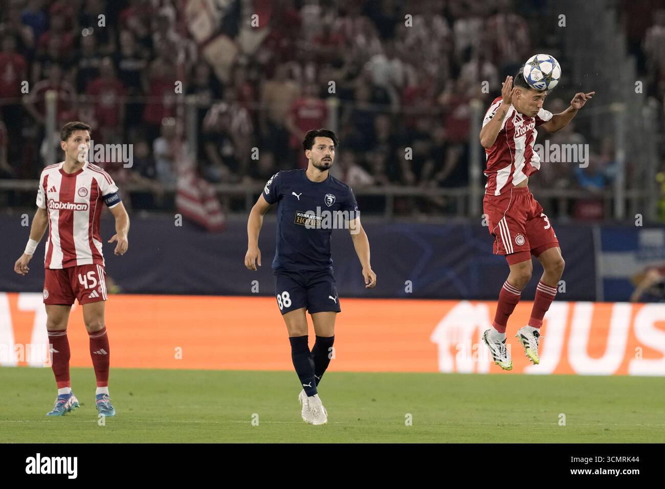 Olympiacos' Francisco Ortega jumps for the ball against Pafos' Pepe ...