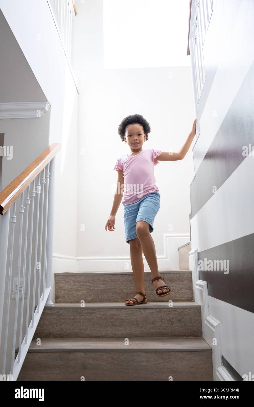 African American girl descending staircase at home entryway under ...