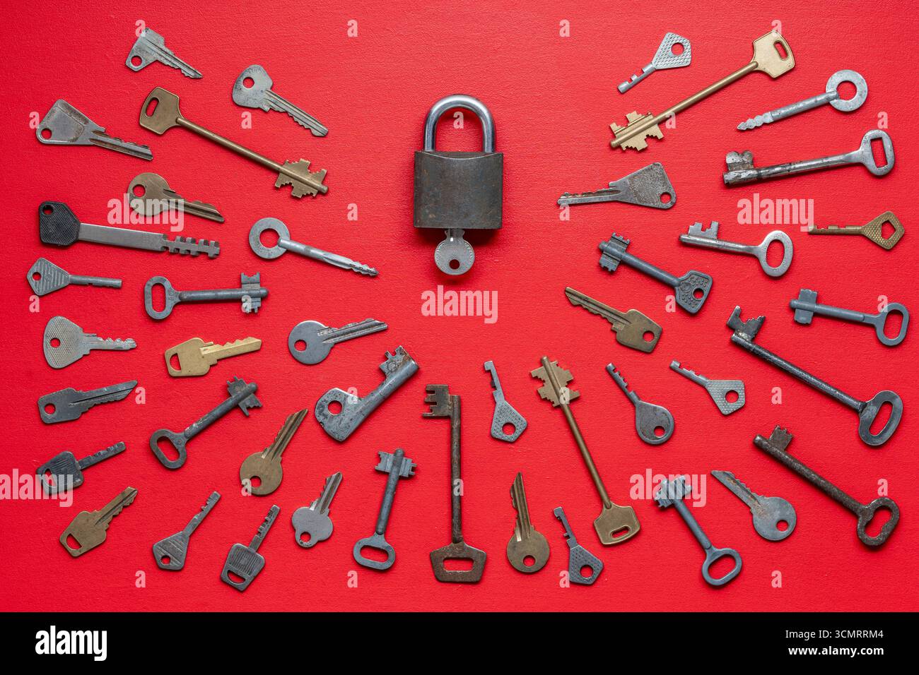 One lock and many different old keys on red background, top view, close ...