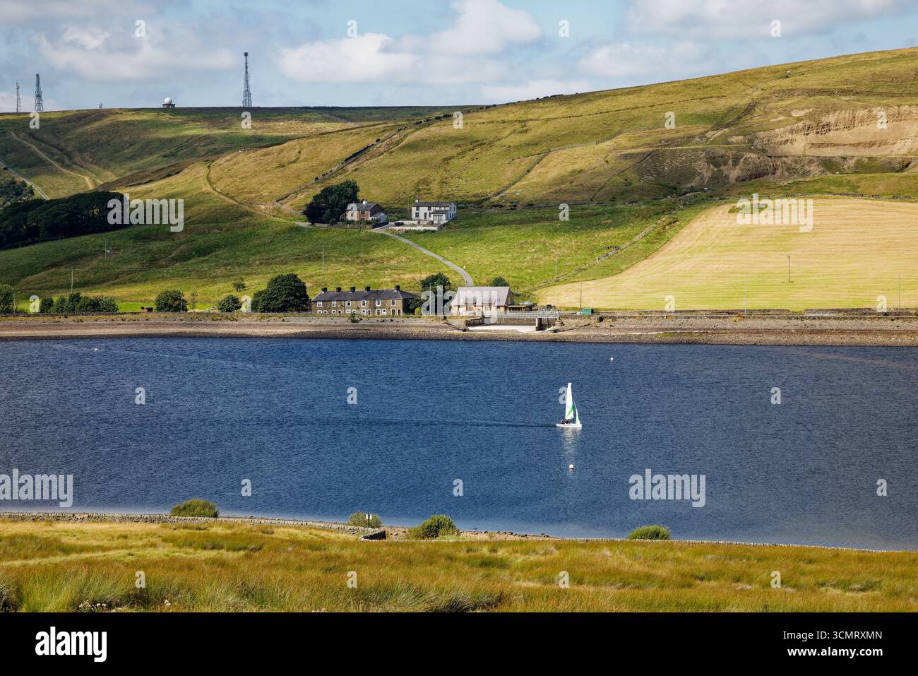 A yacht sails on Clowbridge Reservoir with a sunlit hillside int eh ...