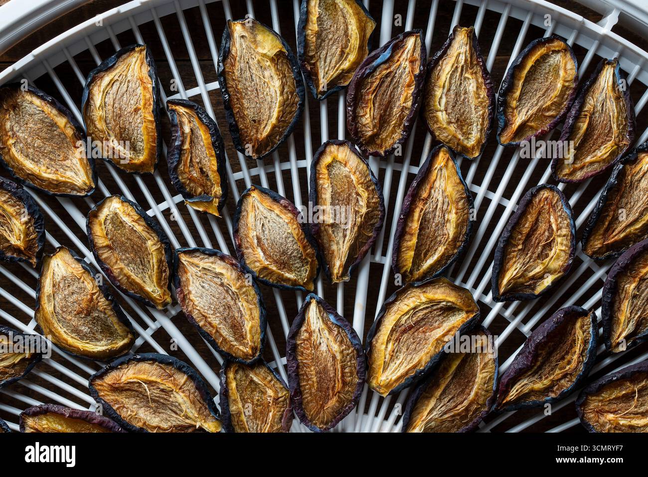 Dry pitted plums on a drying tray for dehydrator, close up. A way to ...