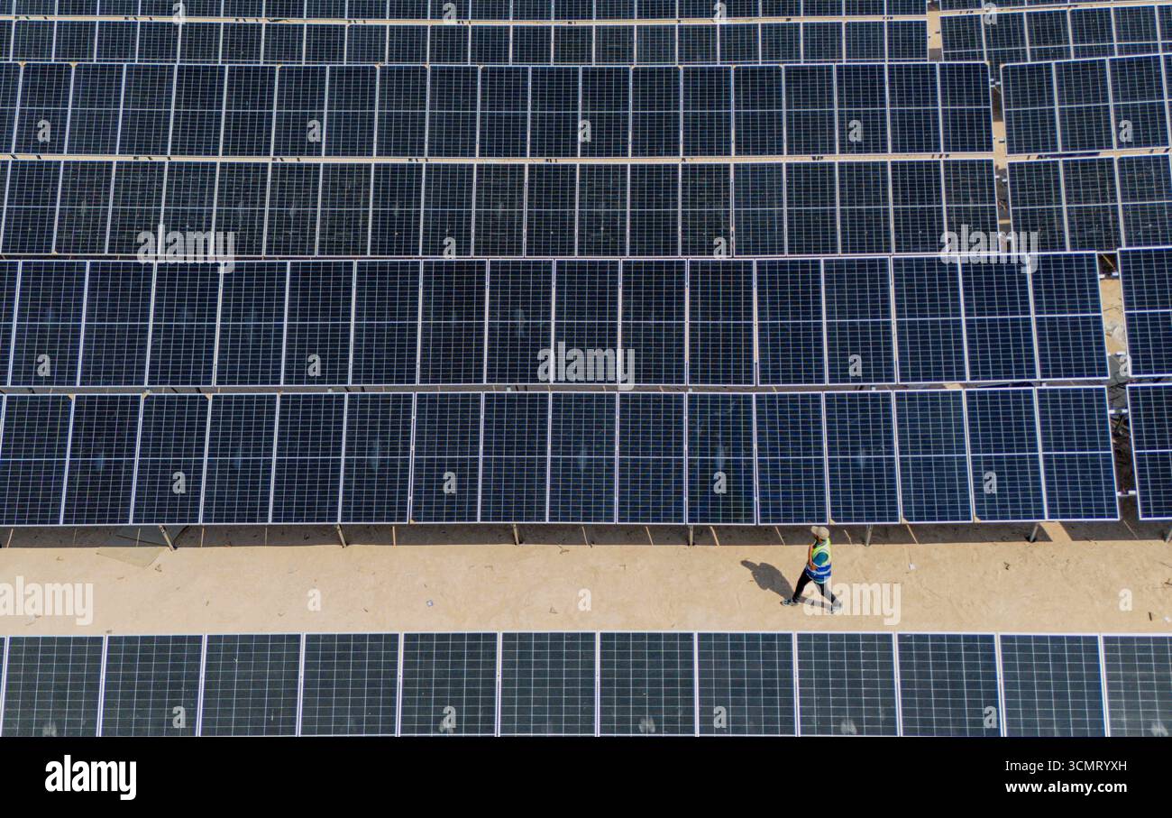 A worker walks past panels at a newly opened industrial-scale solar ...