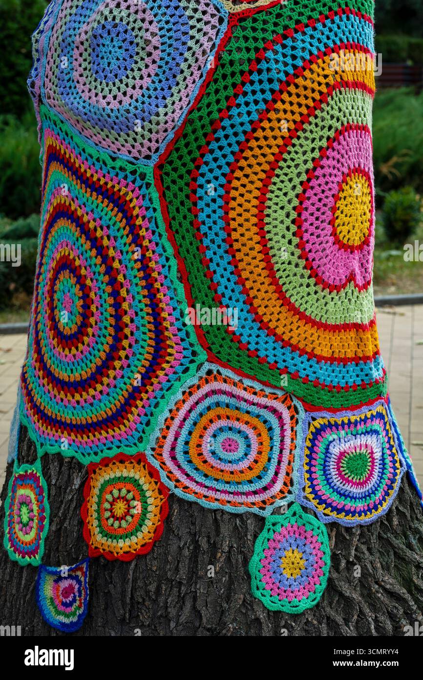 Colorful crochet knit on a tree trunk in Kyiv, Ukraine. Street art goes ...