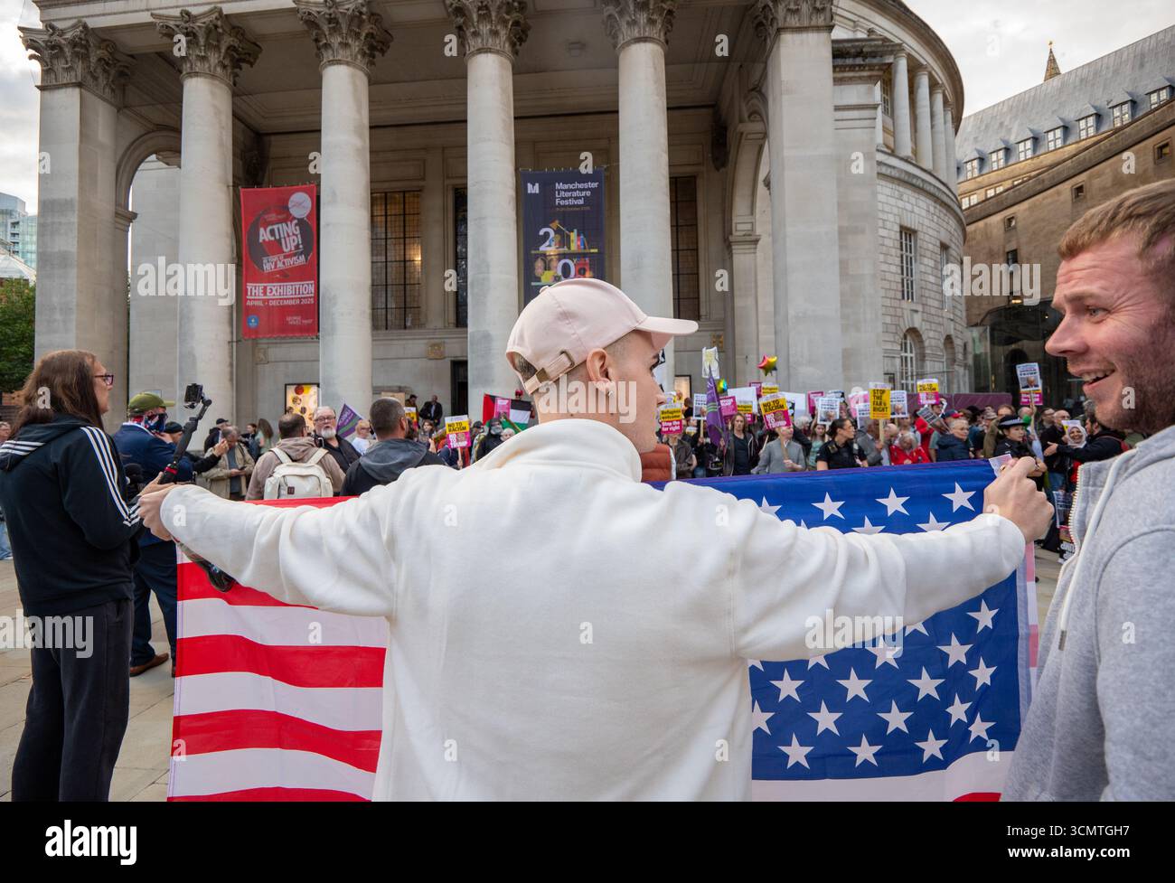 Man holds USA flag facing anti Trump protest. Anti trump supporters ...