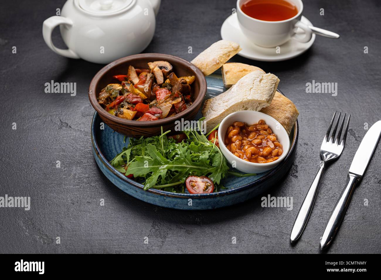 English breakfast with baked beans, ciabatta, and vegetable ragout on ...