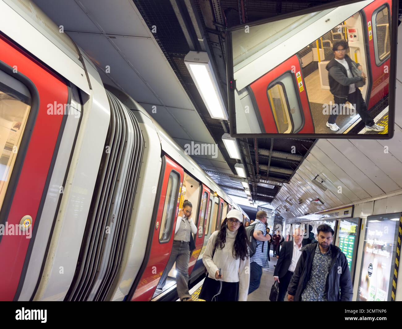 Commuters step off a London Underground train onto a crowded narrow ...