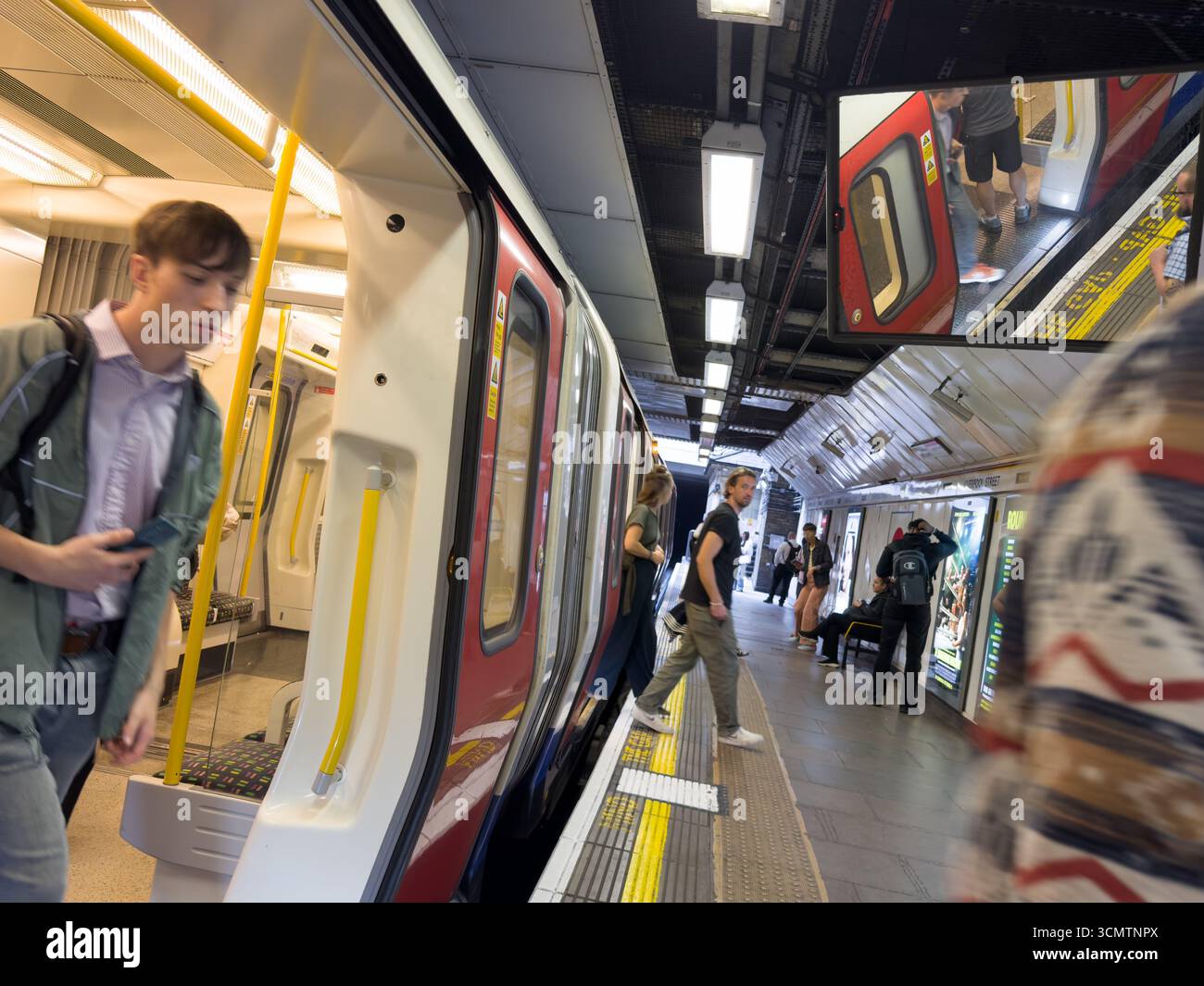 Commuters step off a London Underground train onto a narrow platform at ...
