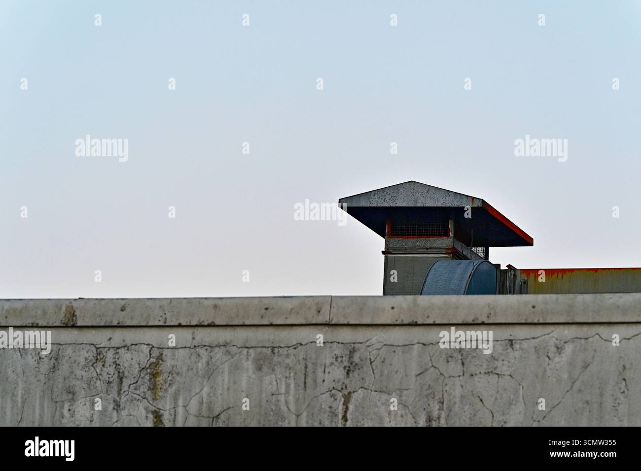 A square column supports a small roofed ventilation hood with open mesh ...