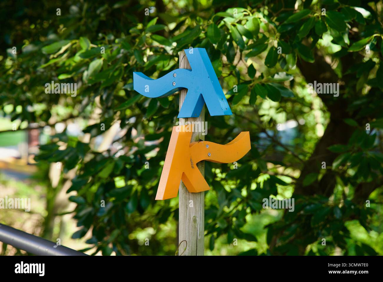 Colorful K‑shaped wayfinding arrows are fixed to a wooden post among ...
