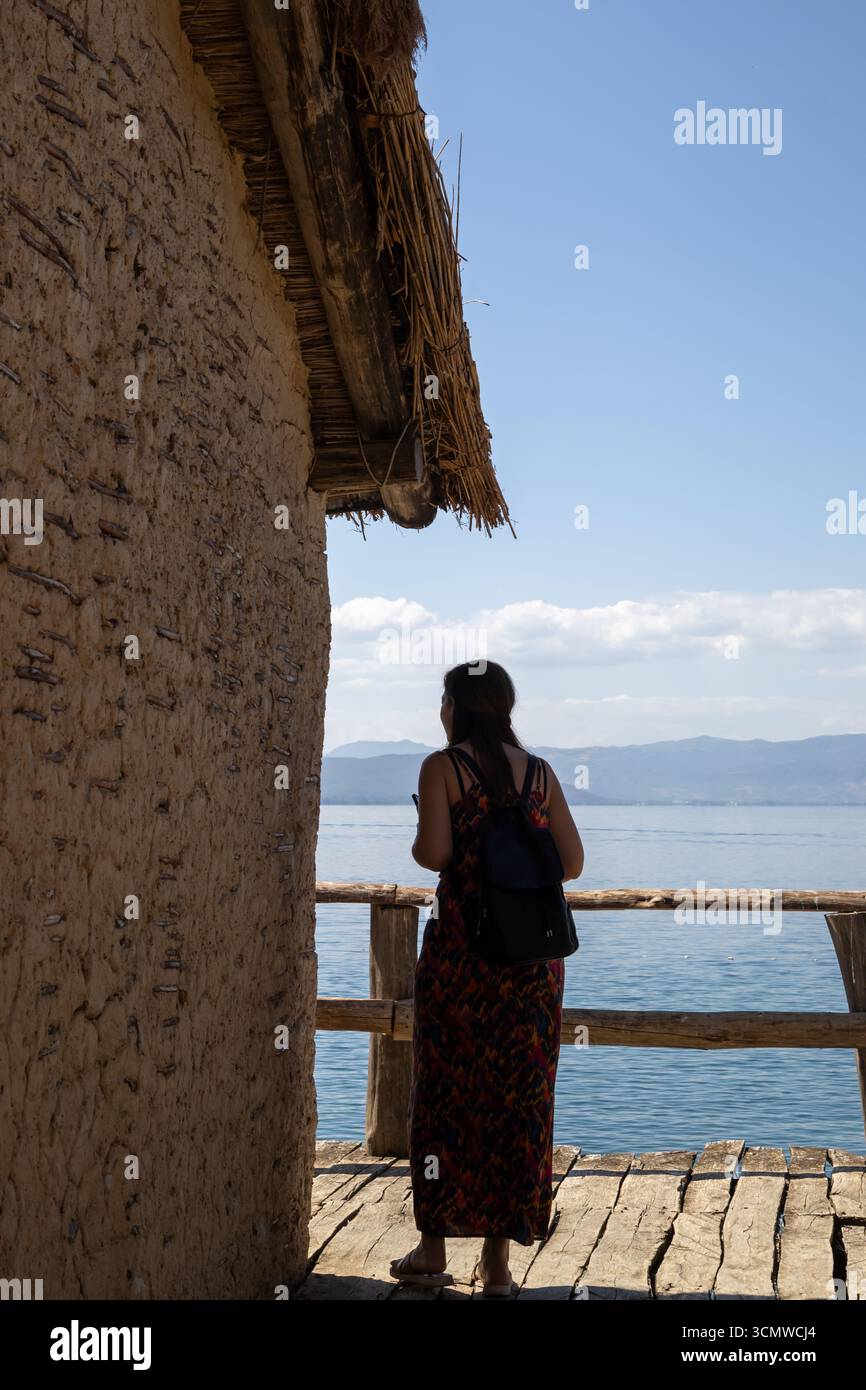 a woman with her back to the camera stands on a wooden platform ...