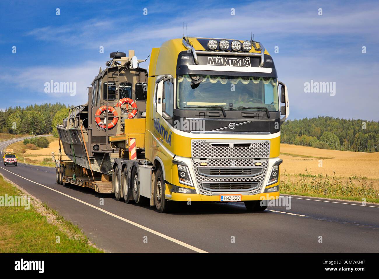 Yellow Volvo FH16 truck Mantyla hauls naval vessel on low loader ...