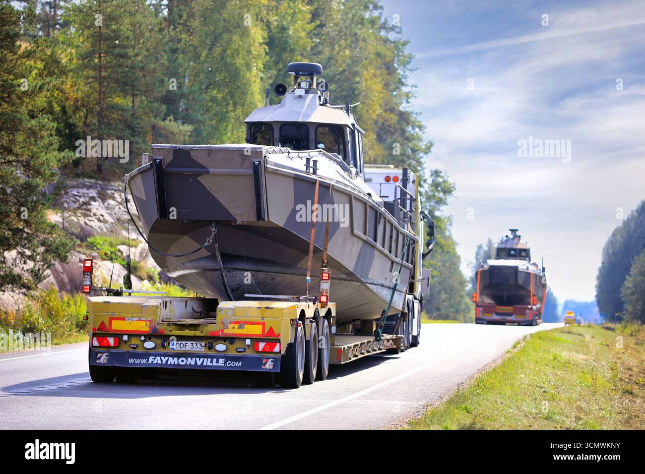 Fleet of two trucks transport landing crafts on low loader trailer as ...