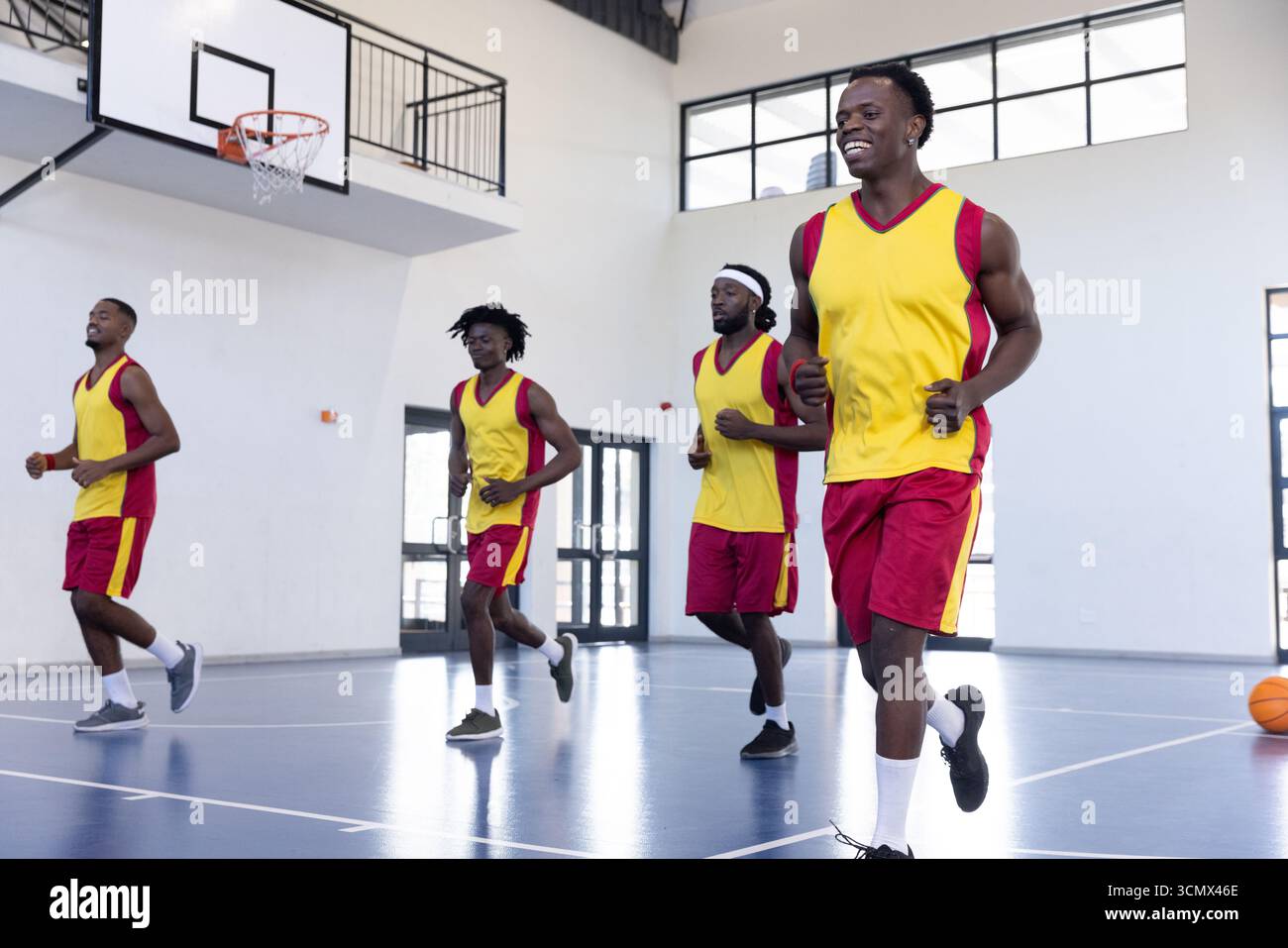 African american basketball teammates jogging on court under hoop with ...