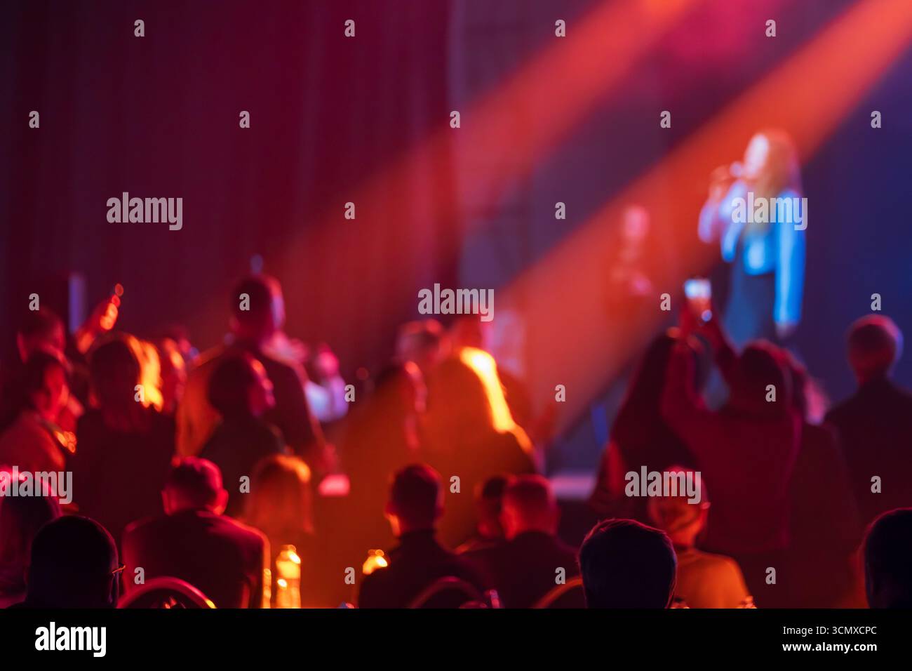 Audience enjoys live performance on stage illuminated by striking red ...