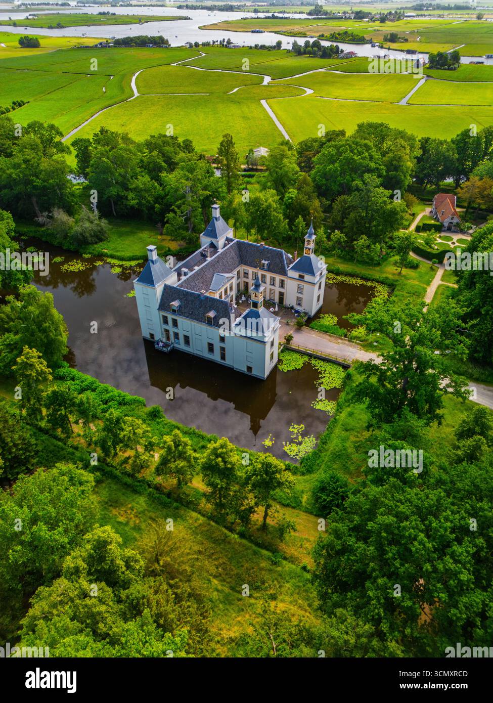A grand historic manor with towers sits on an island surrounded by a ...