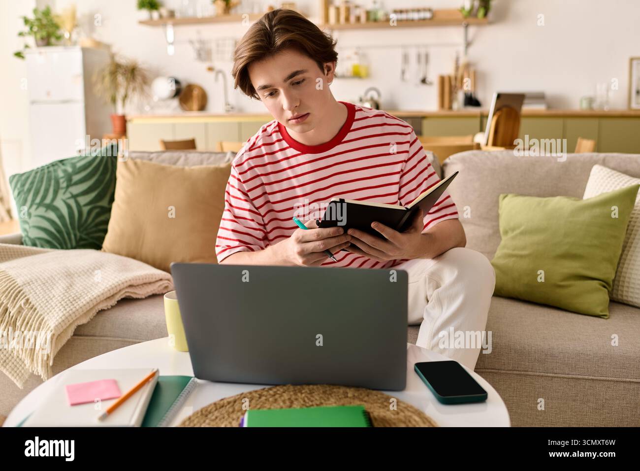 A young man focuses on his online classes while seated in his modern ...