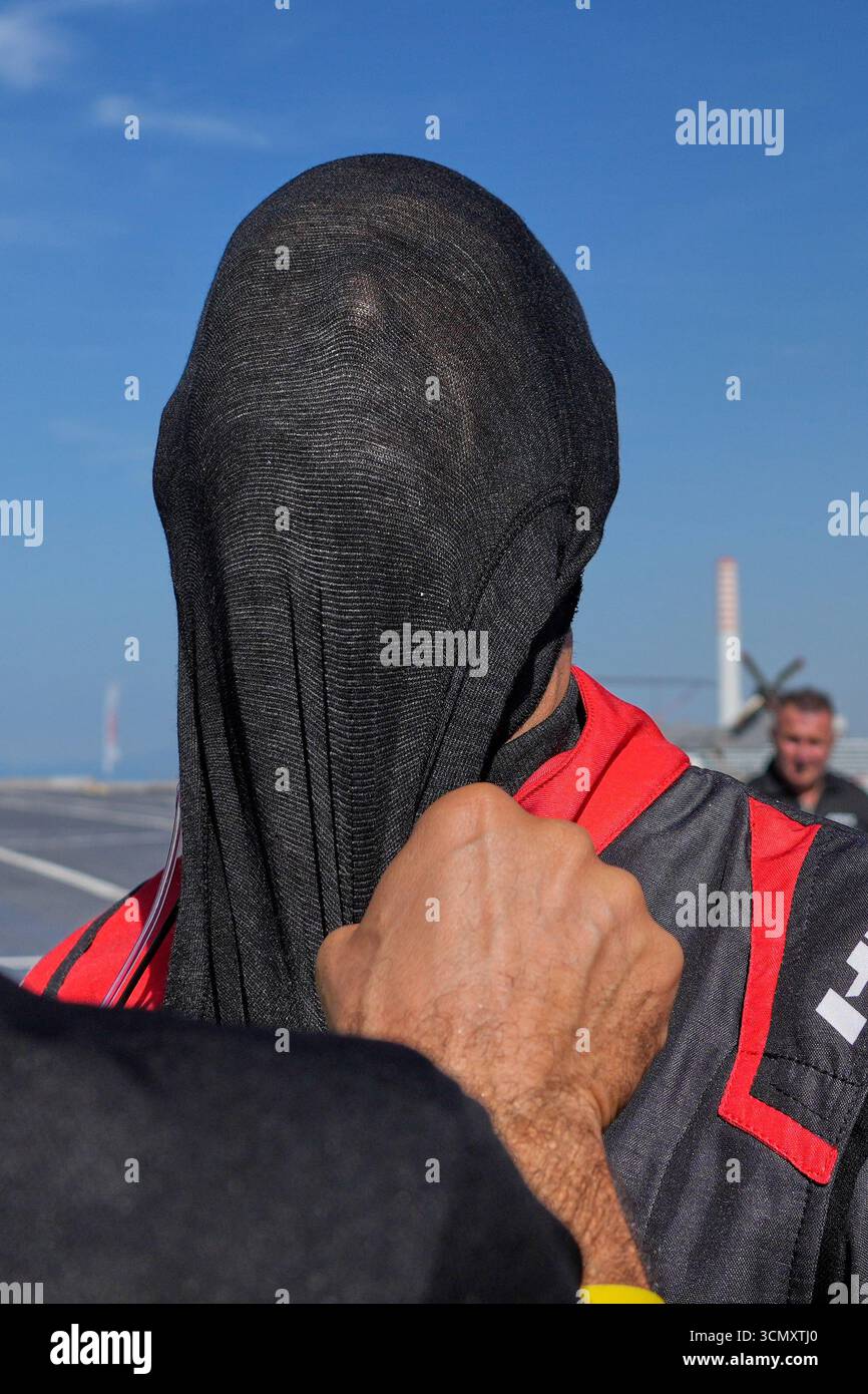 Italian driver Fabio Barone is helped to remove his protective mask ...