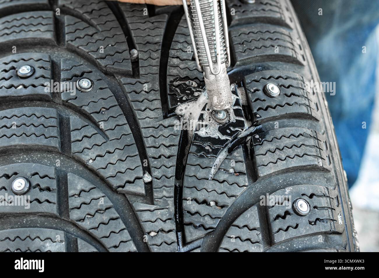 Close-up of a new metal stud being driven into a lubricated hole in a ...