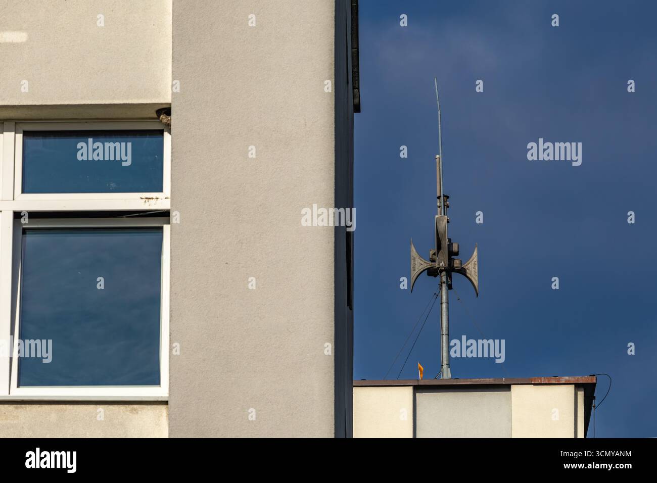 An alarm siren mounted on the roof of a building, the siren emits a ...