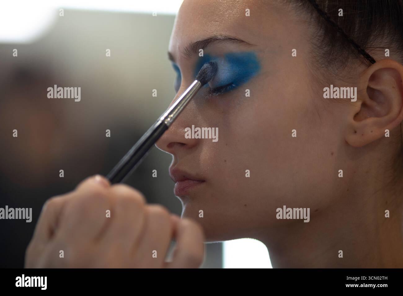 A makeup artist paints a model's eyelid blue backstage during the Agatha Ruiz de la Prada Spring ...