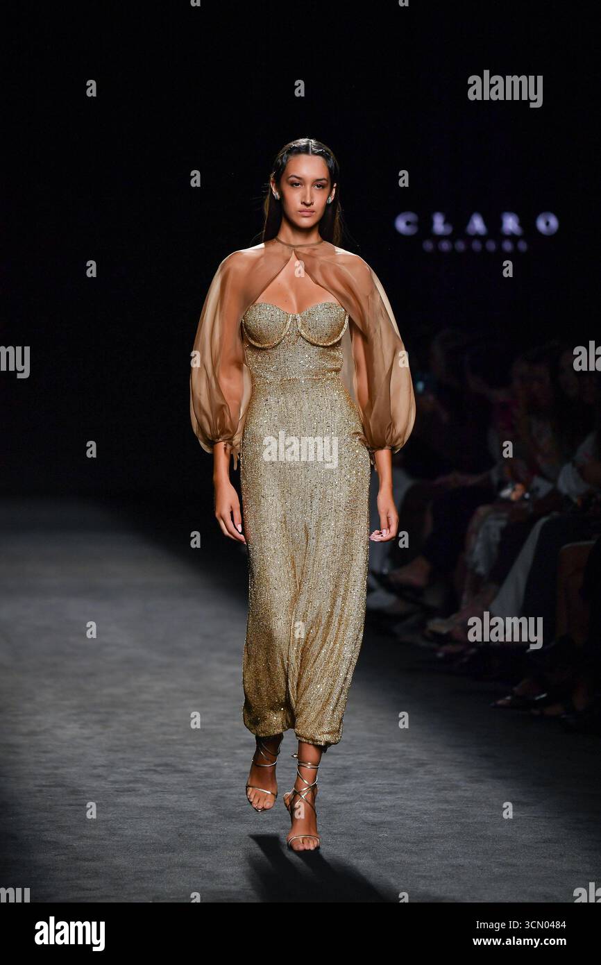 A model walks the runway wearing a design by Claro Couture during ...