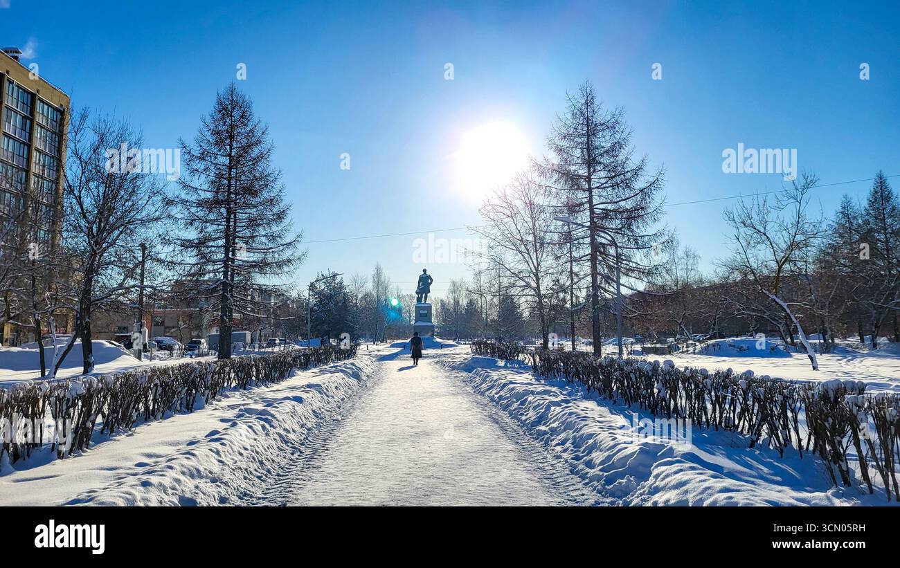 Snow-covered alley in a northern provincial town leading to a monument ...