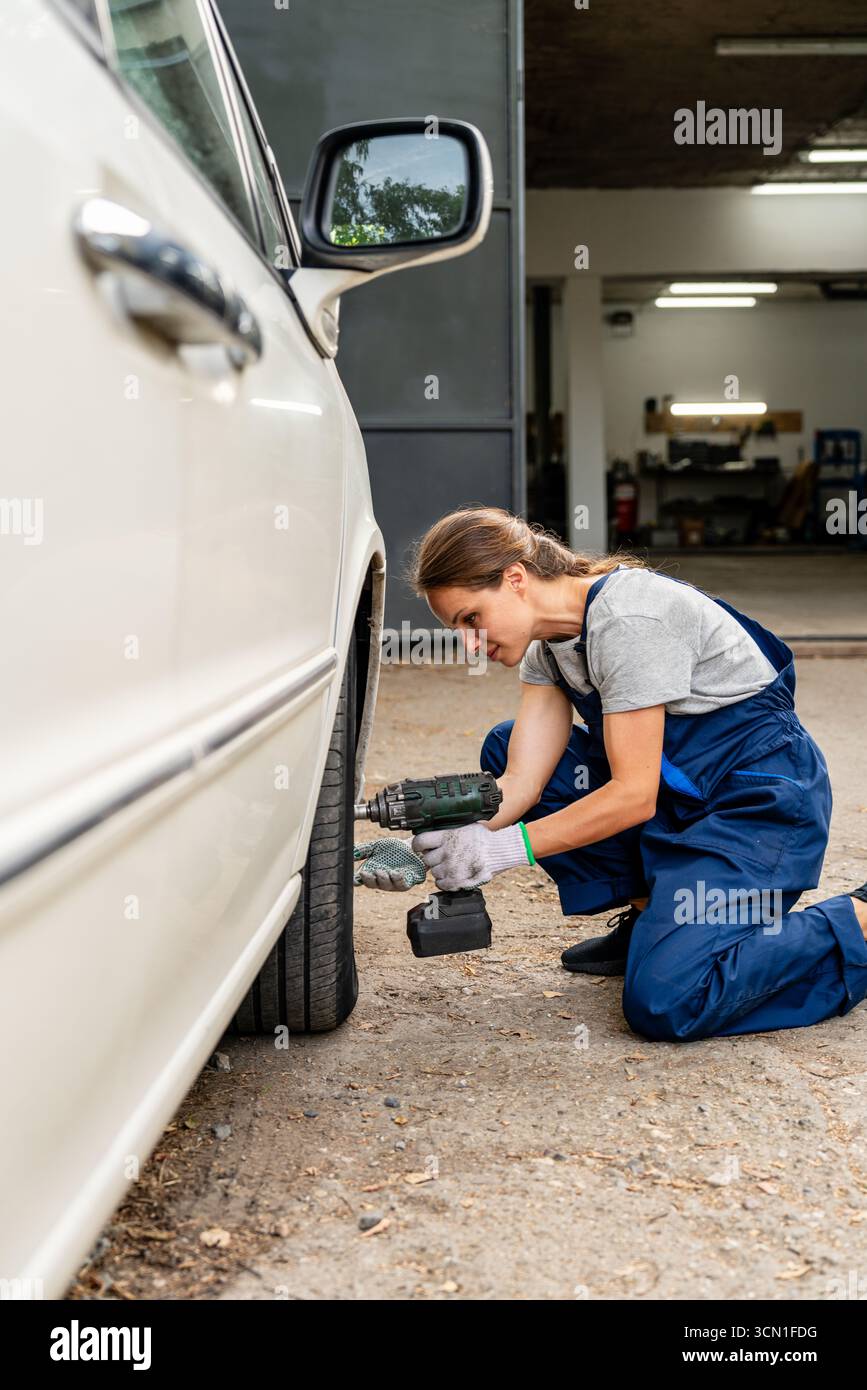 Female tire shop worker changing car wheel in garage Stock Photo - Alamy