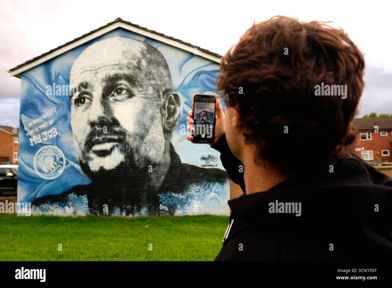 A fan takes a photo of a mural of Manchester City manager Pep Guardiola ...