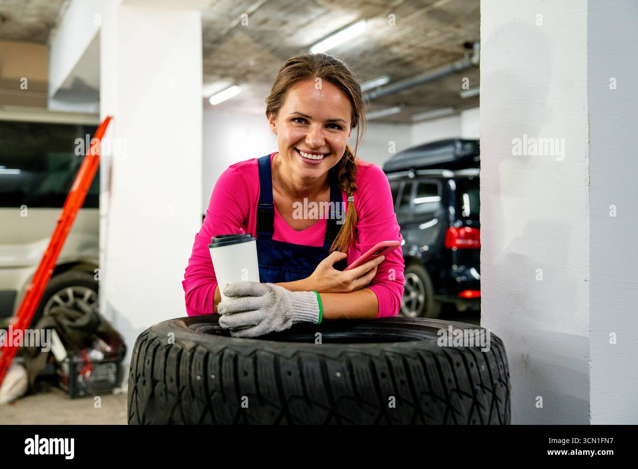 Woman at work. Female auto mechanic taking coffee break in local auto ...