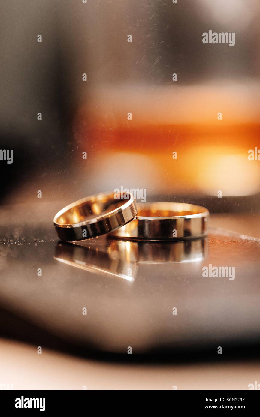 Two gold wedding rings on mirror with warm romantic light and soft ...