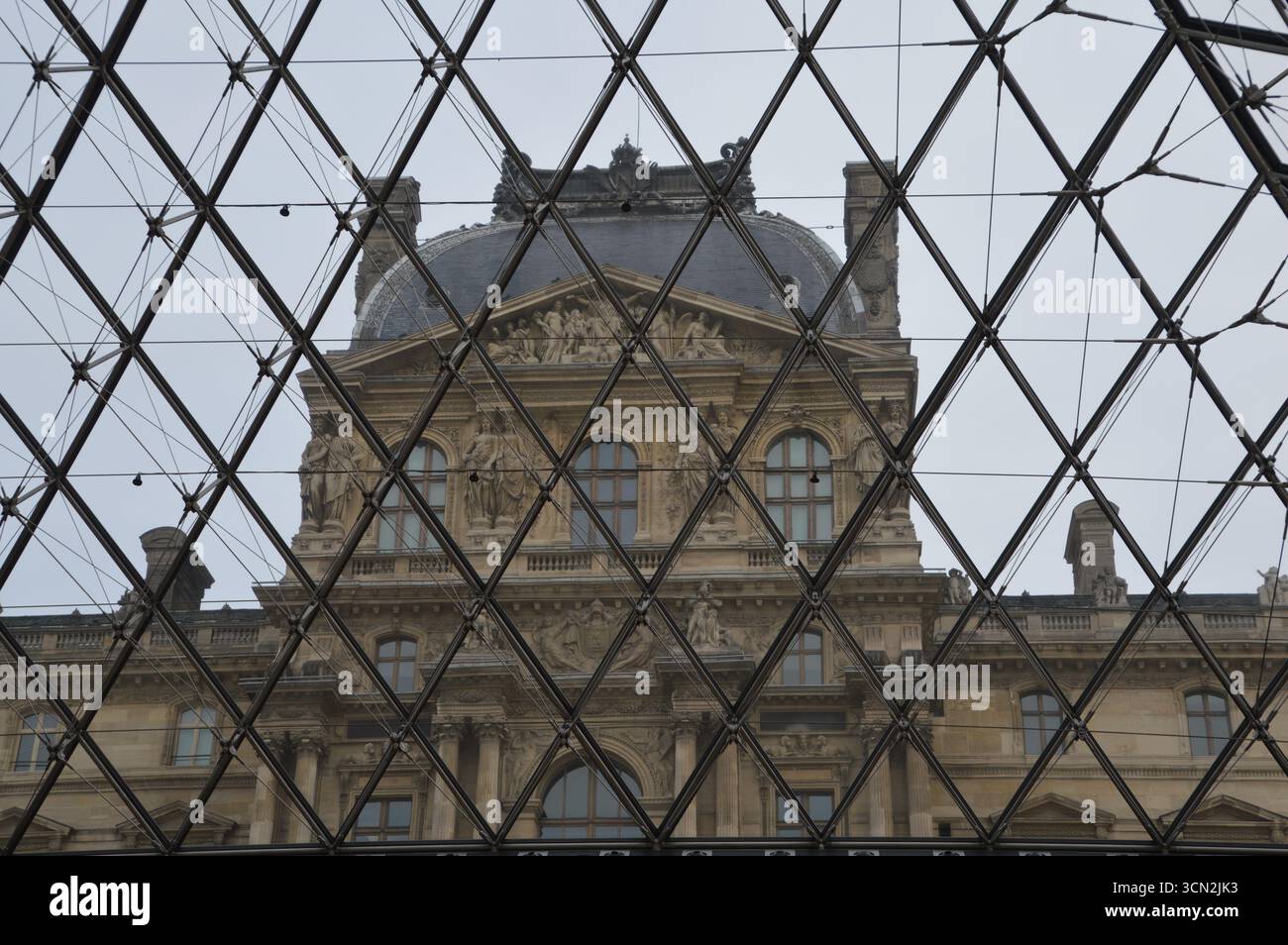 View of the Louvre Museum through the glass pyramid structure on a ...