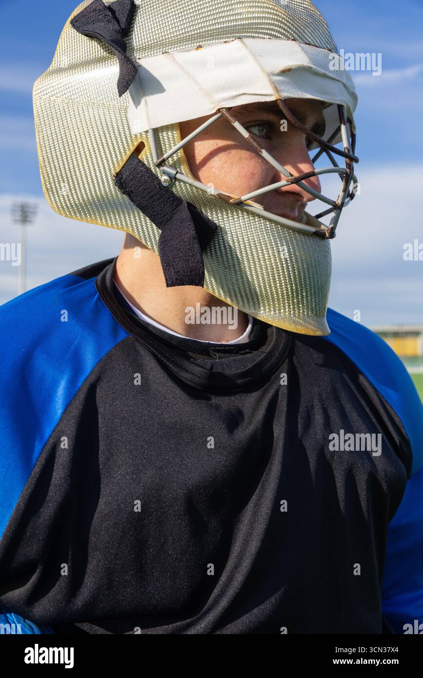 Goalkeeper in helmet and padded jersey on green field under clear sky ...