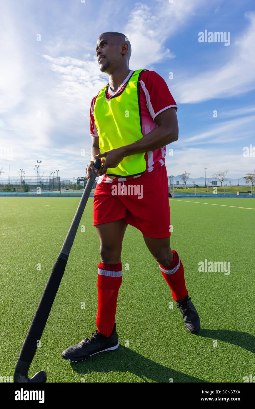 Hockey stick leaning on yellow vest near goal posts on green turf under ...