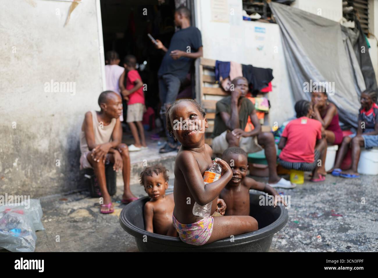 Children bathe at a makeshift shelter for people displaced by gang ...