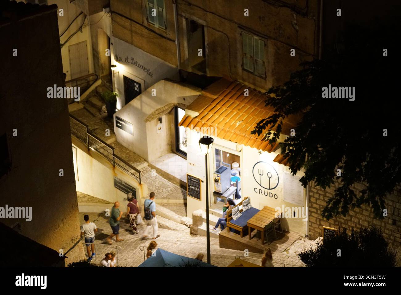 Night Scene Of A Small Italian Restaurant With Outdoor Seating And Warm ...