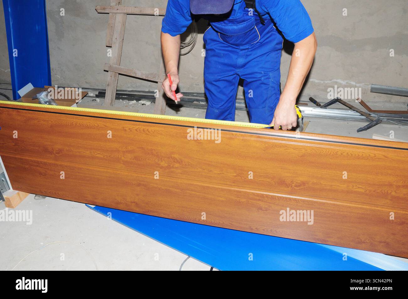 Garage door repair. Contractor measuring garage door board with measure ...