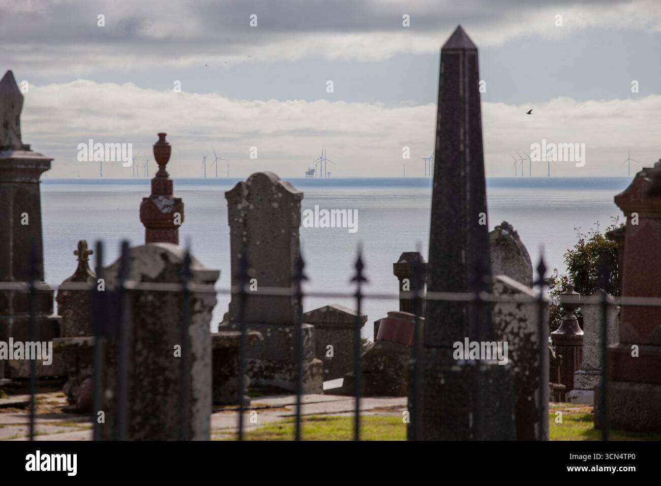 In the background, wind turbines, and in the foreground, a cemetery ...