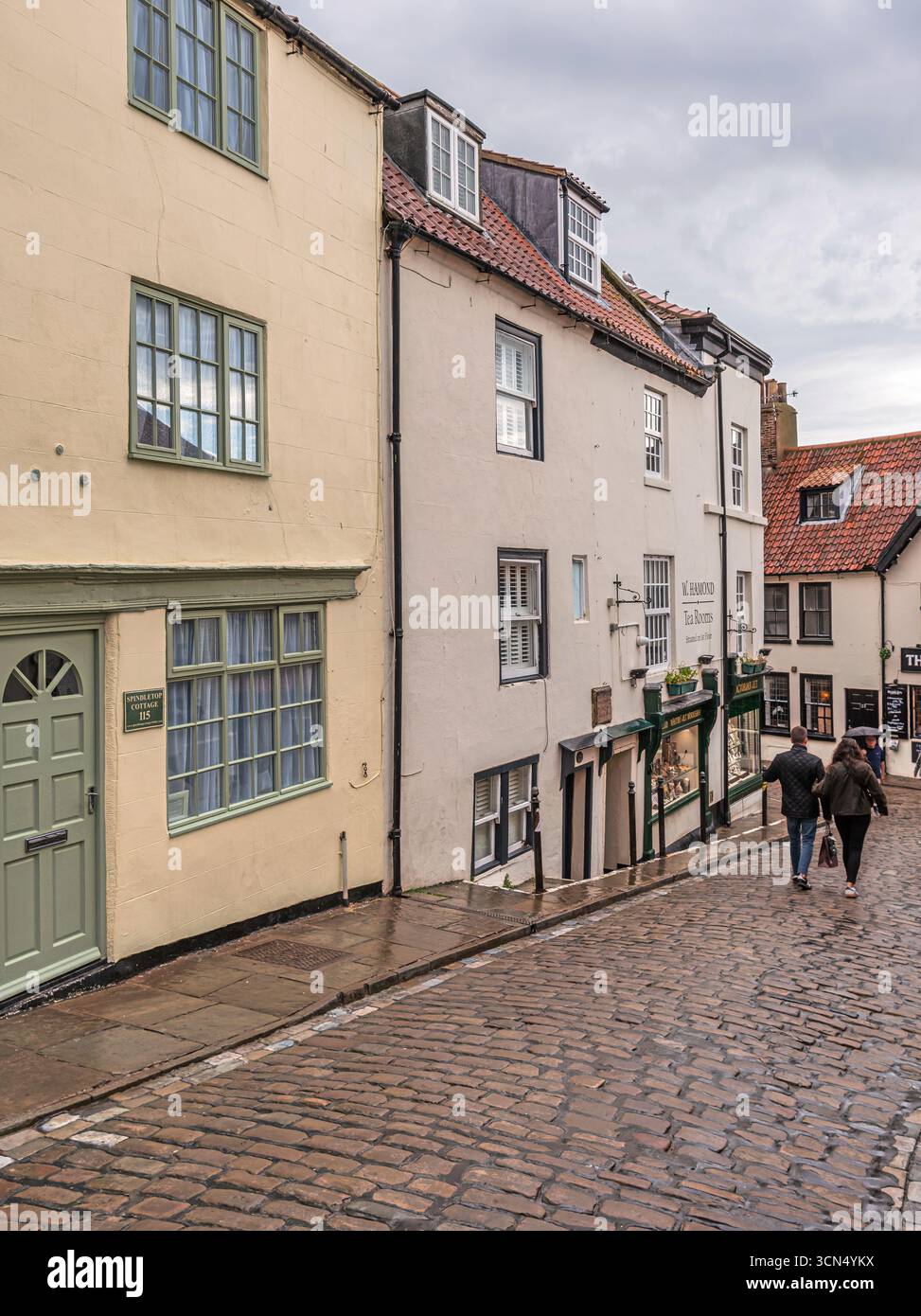 A row of cottages and a shop on a quaint cobbled street after a rain ...