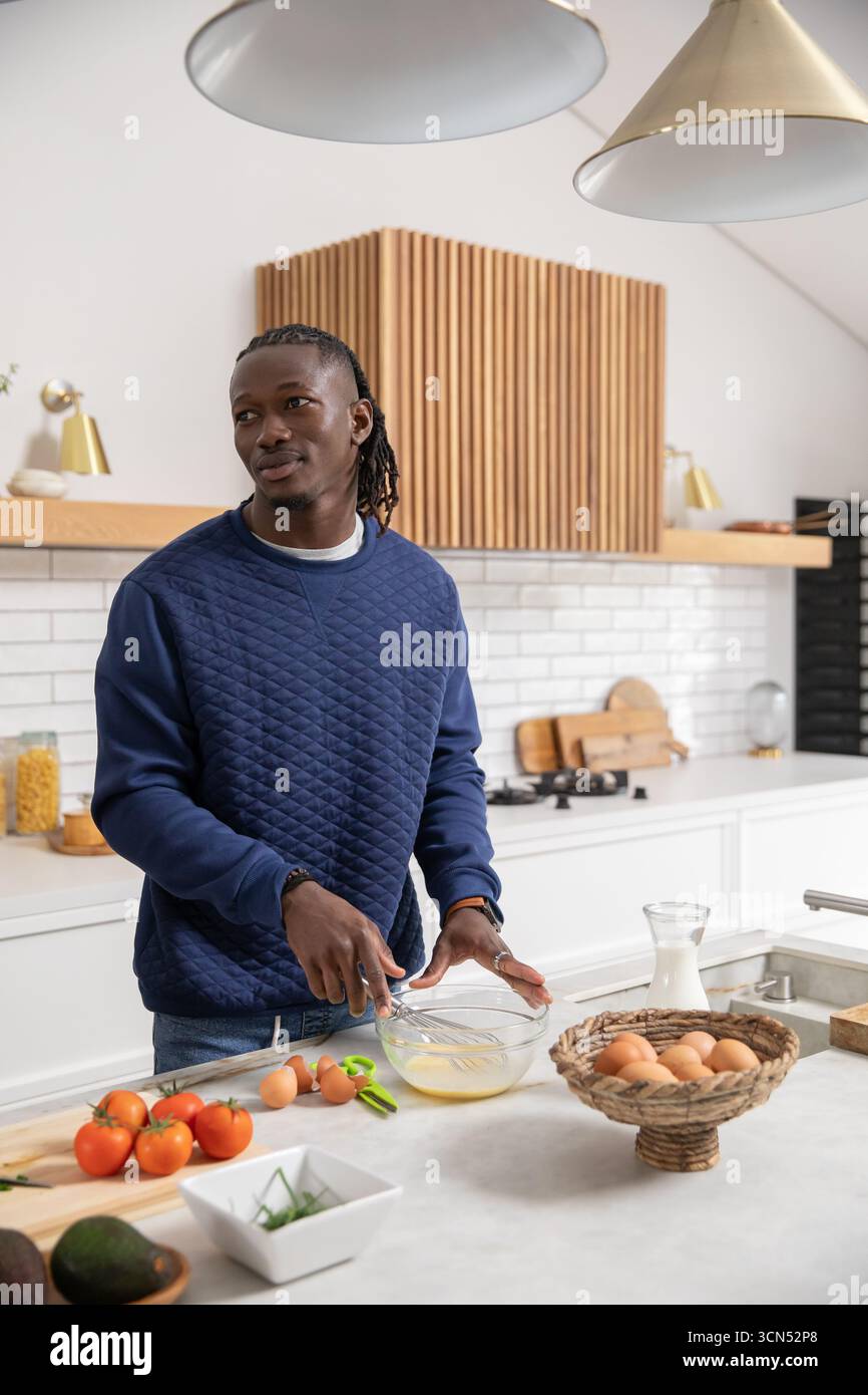 African american man whisking eggs in glass bowl at marble island with ...