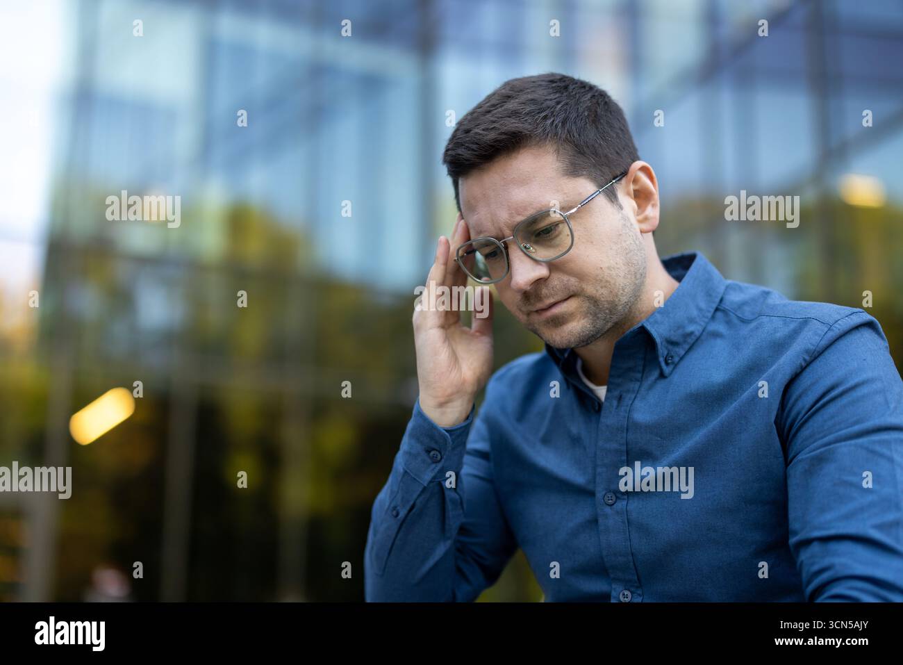 Young man experiencing a severe headache, holding his temple with a ...